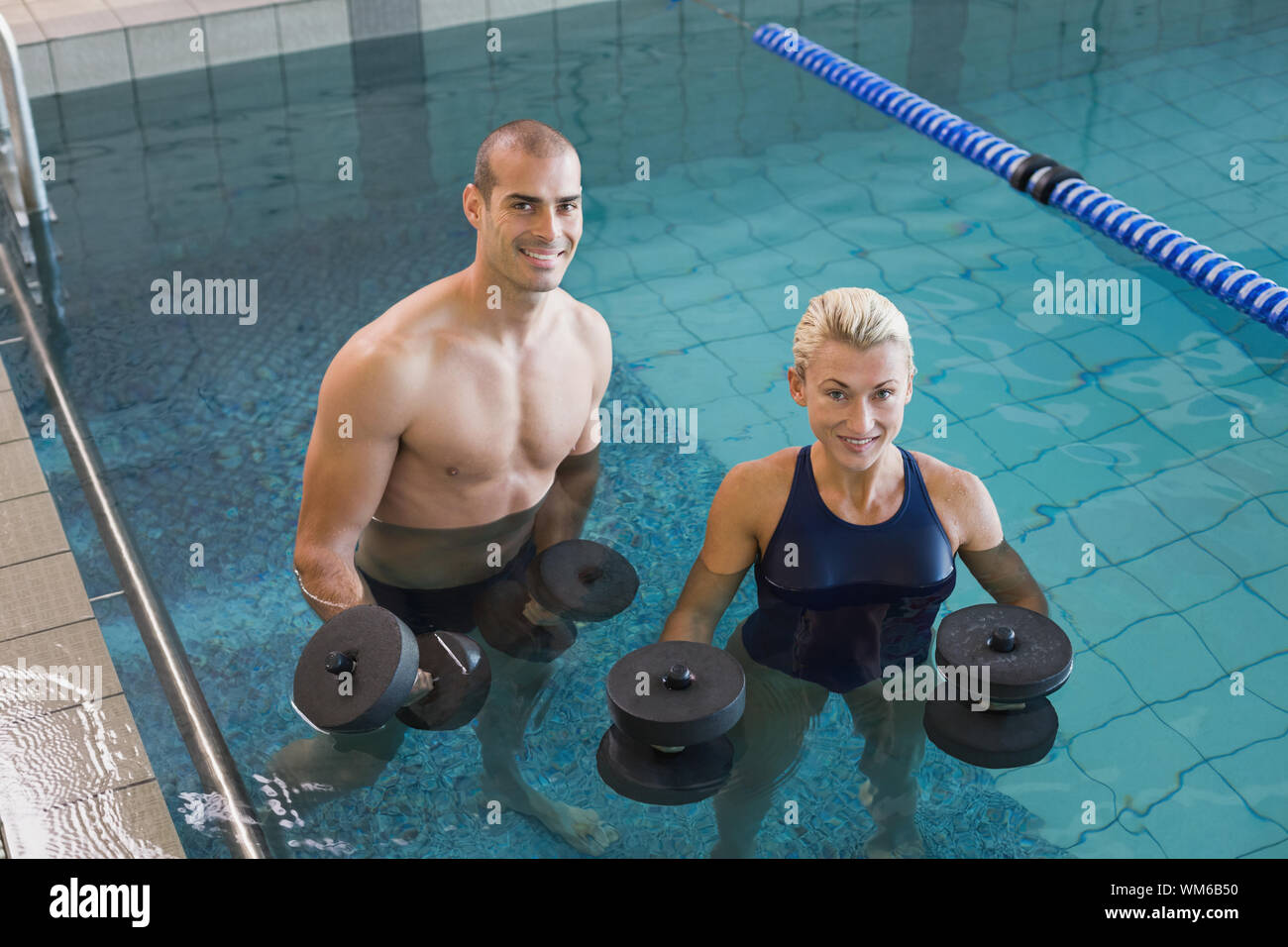 Portrait of fit swimmers working out with foam dumbbells in swimming ...