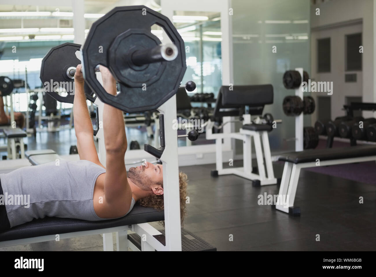 Side view of young muscular man lifting barbell in the gym Stock Photo ...