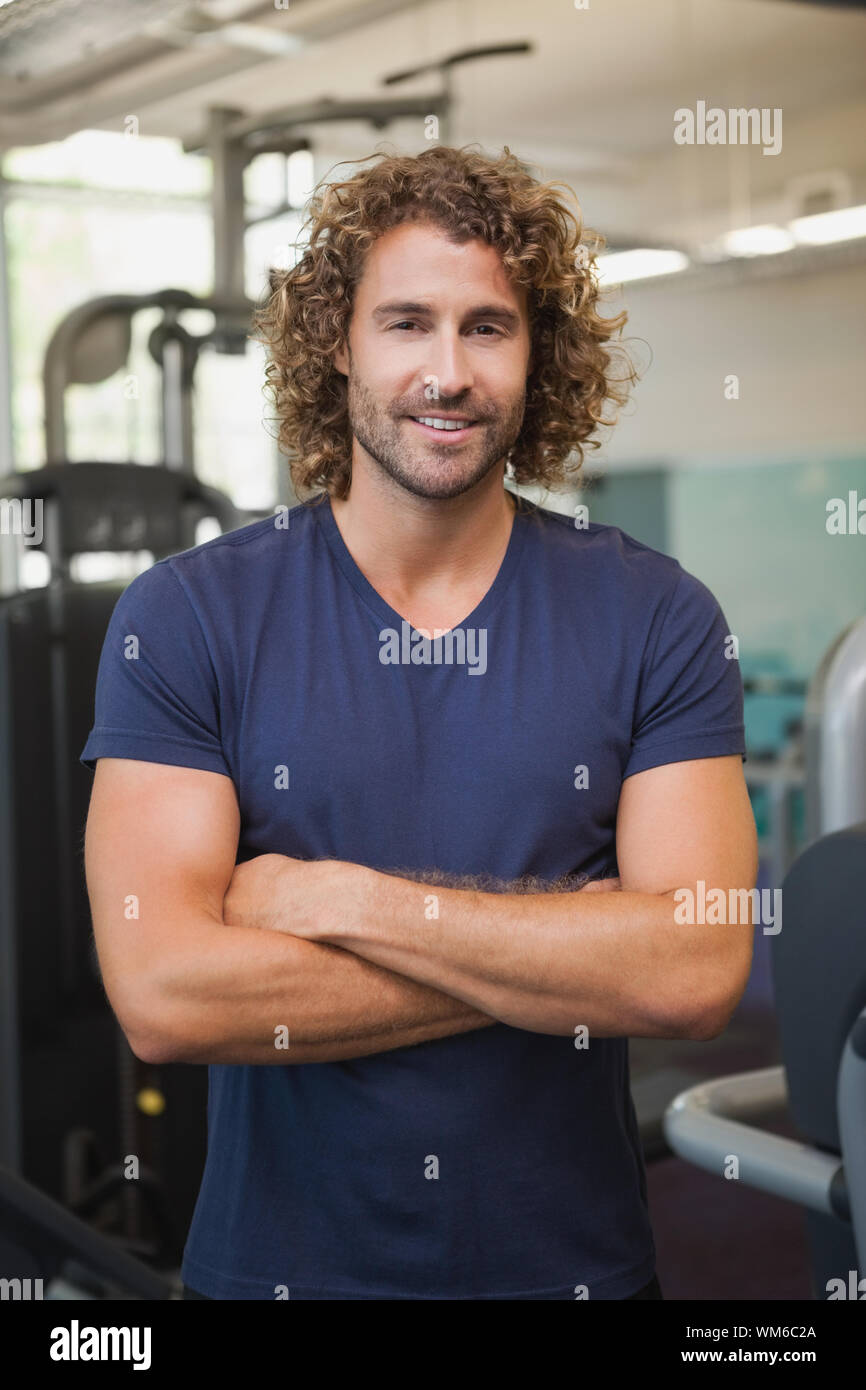 Portrait of a smiling handsome trainer with arms crossed standing in ...
