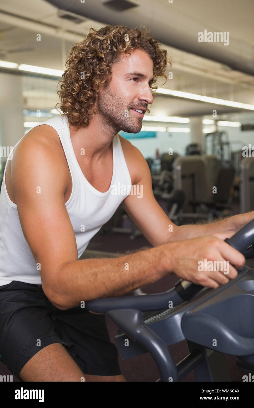 Side view of a young man working out on exercise bike at the gym Stock ...