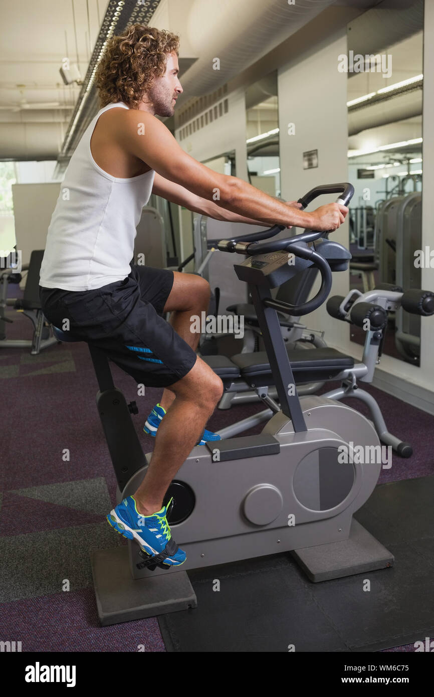 Side view of a young man working out on exercise bike at the gym Stock ...
