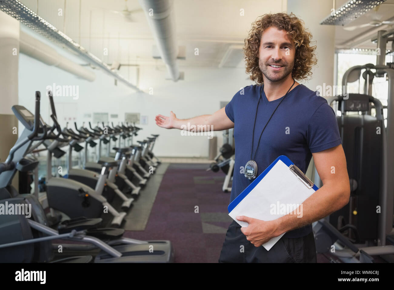 Portrait of a smiling handsome trainer with clipboard standing in the ...