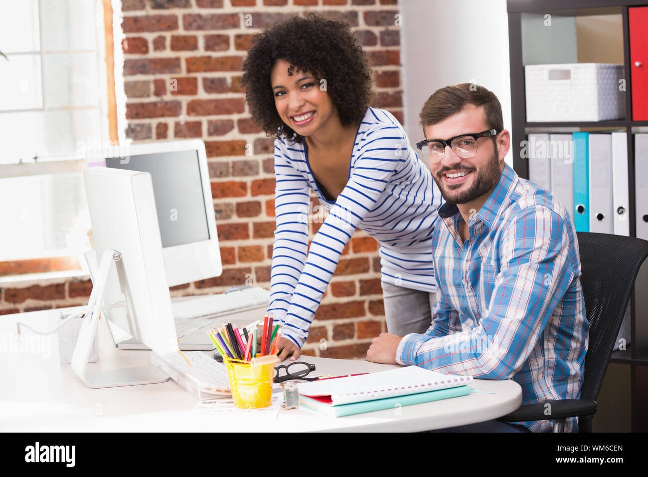 Portrait of two smiling photo editors using computer in the office ...