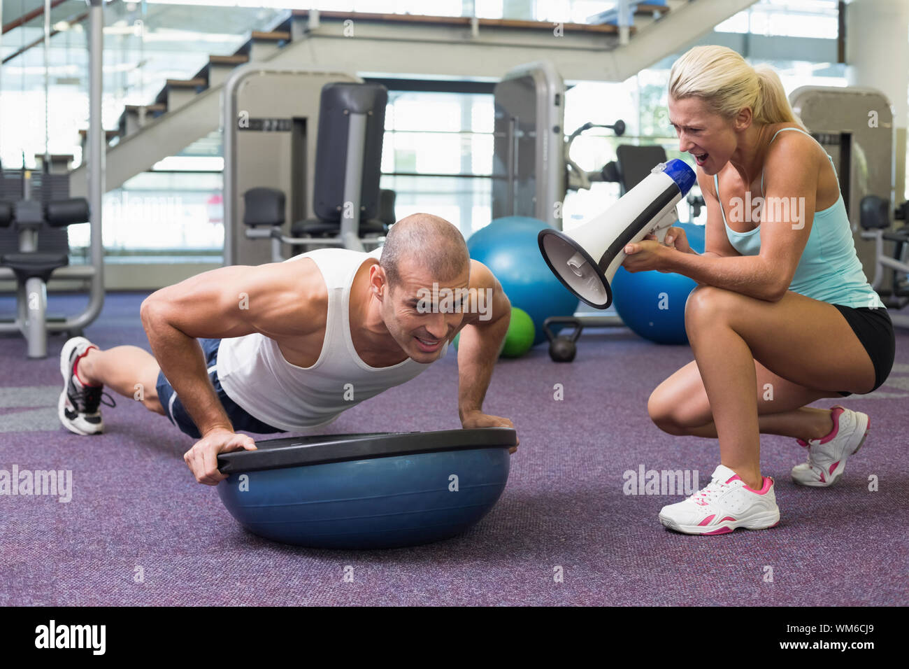 View of a female trainer assisting man with push ups at the gym Stock ...