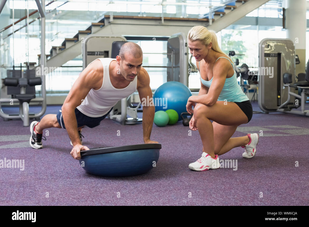View of a female trainer assisting man with push ups at the gym Stock ...