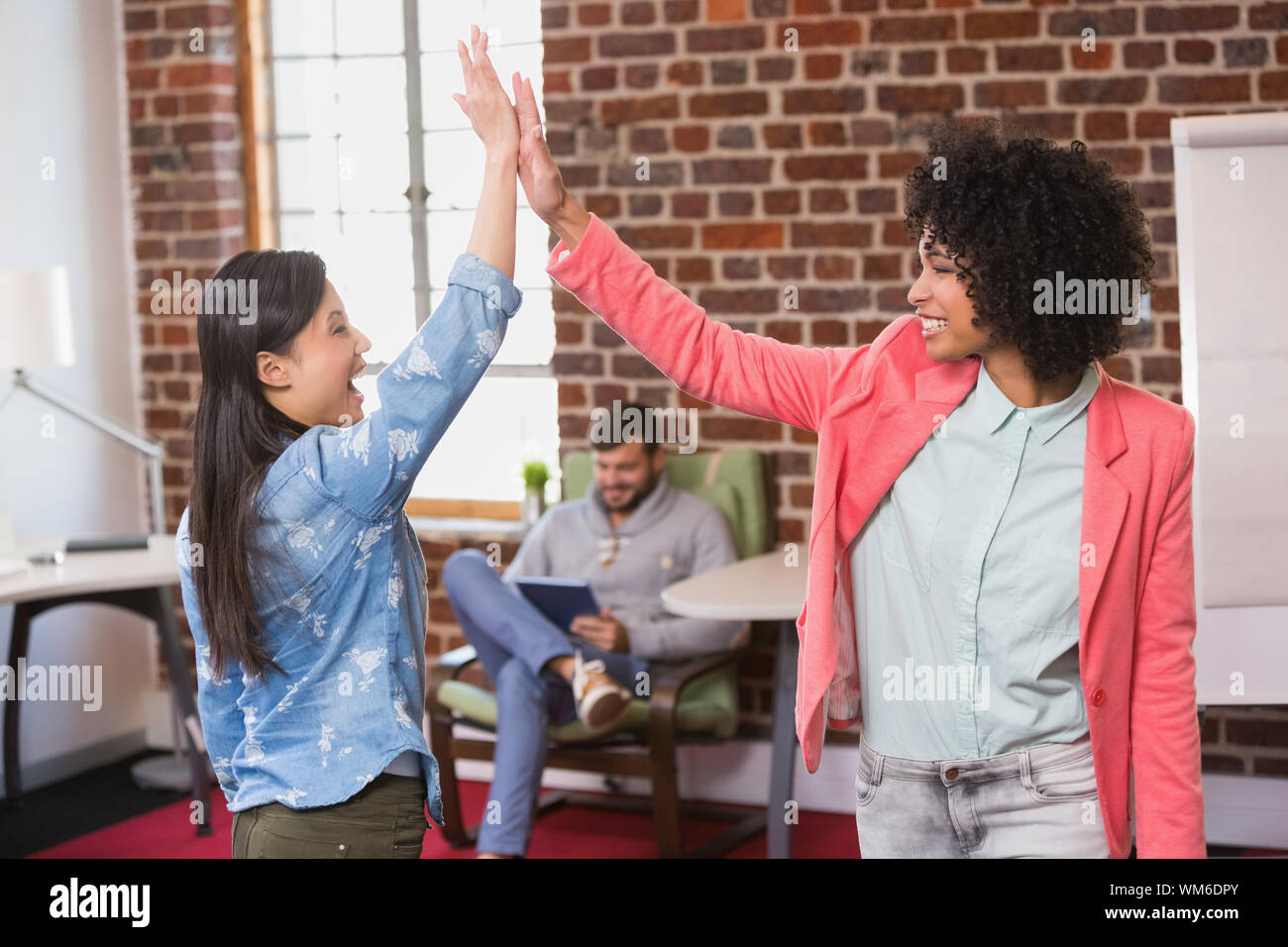 Young female colleagues high fiving in the office Stock Photo - Alamy