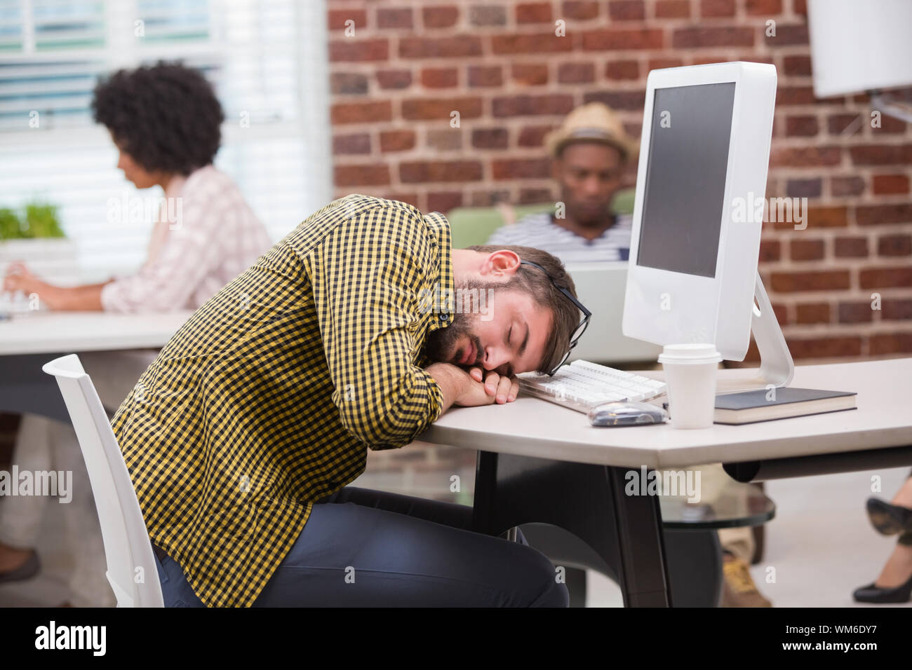 Casual young man resting head on computer keyboard in the office Stock ...