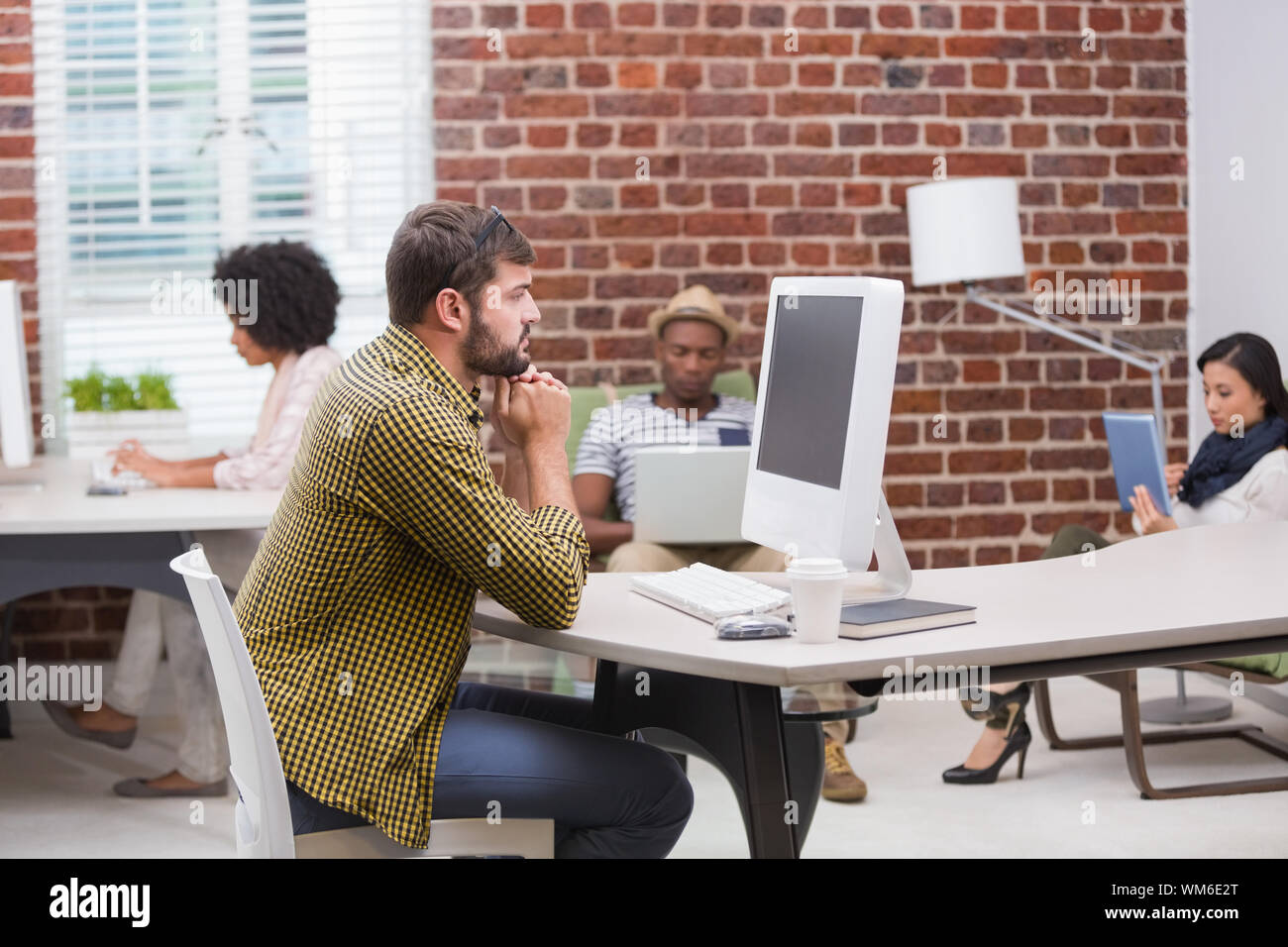 Side view of casual young man using computer in the office Stock Photo ...