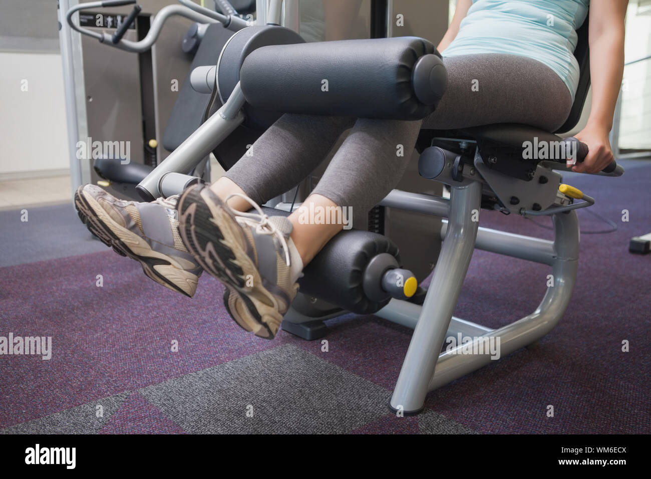 Fit woman using weights machine for legs at the gym Stock Photo - Alamy
