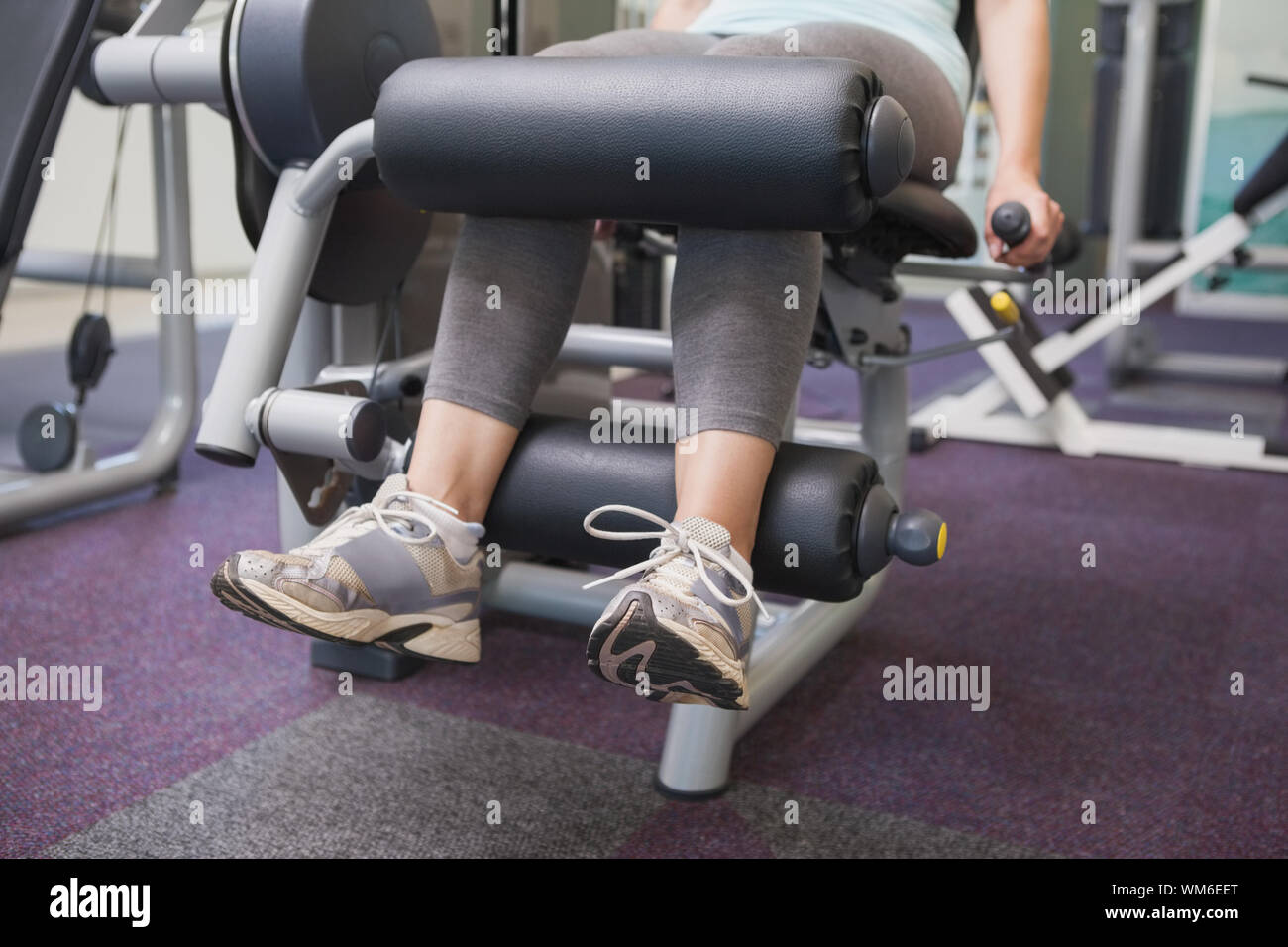 Fit woman using weights machine for legs at the gym Stock Photo - Alamy