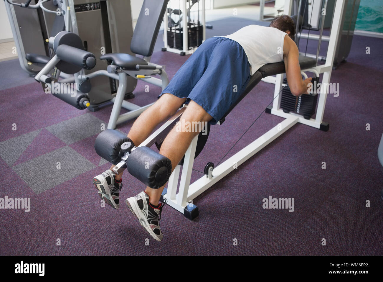 Fit man using weights machine for legs at the gym Stock Photo - Alamy