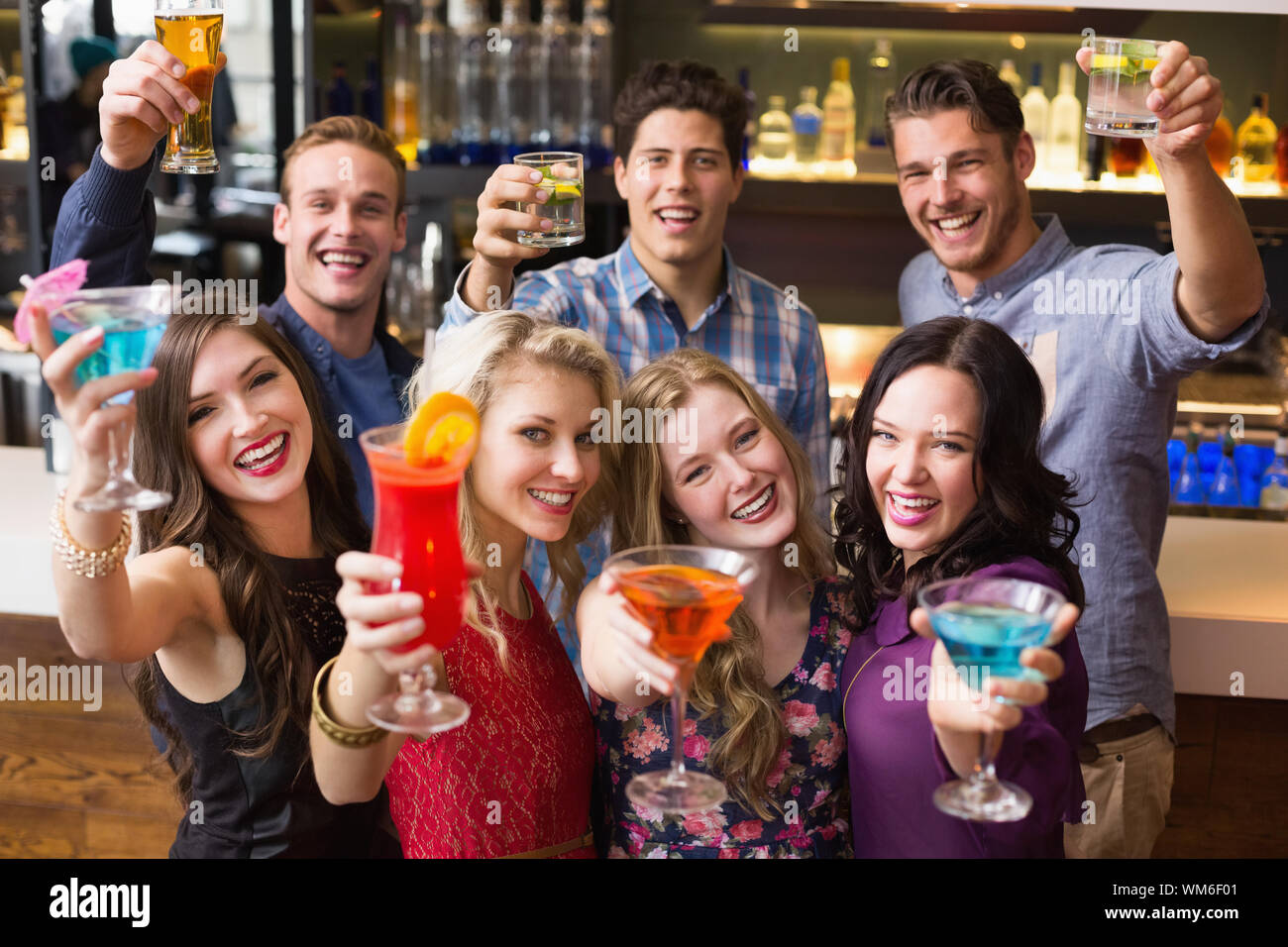 Happy friends drinking cocktails together at the bar Stock Photo - Alamy