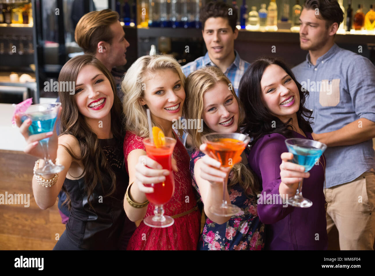 Happy friends drinking cocktails together at the bar Stock Photo - Alamy