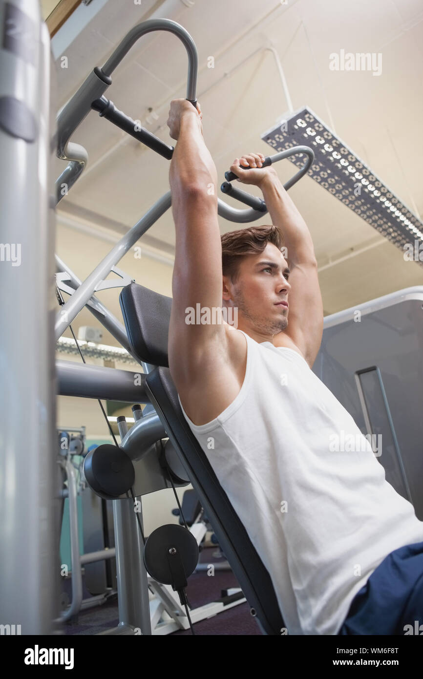 Fit man using weights machine for arms at the gym Stock Photo - Alamy