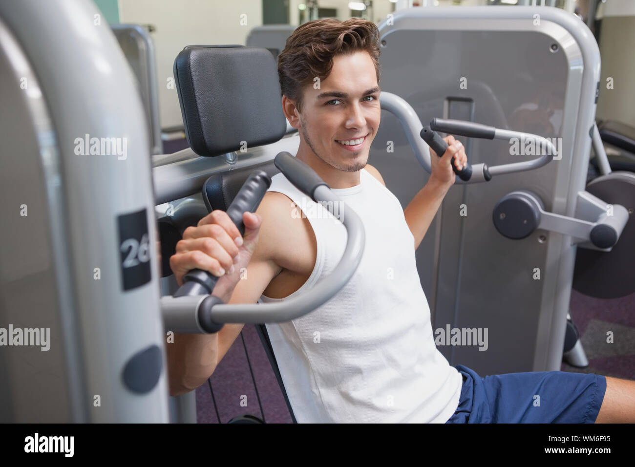Fit man using weights machine for arms at the gym Stock Photo - Alamy