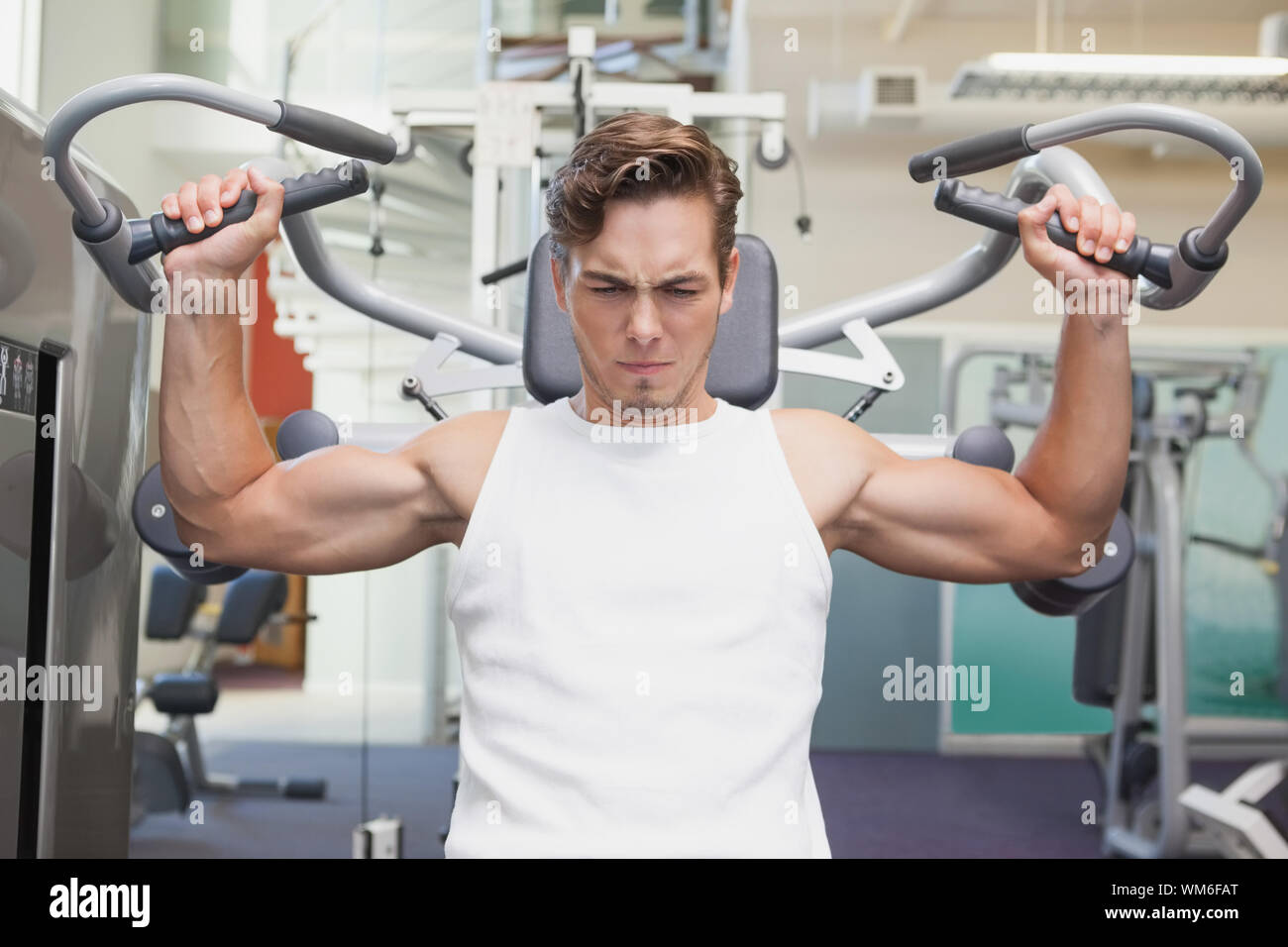 Fit man using weights machine for arms at the gym Stock Photo - Alamy