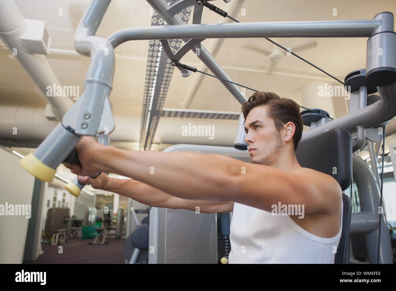Fit man using weights machine for arms at the gym Stock Photo - Alamy