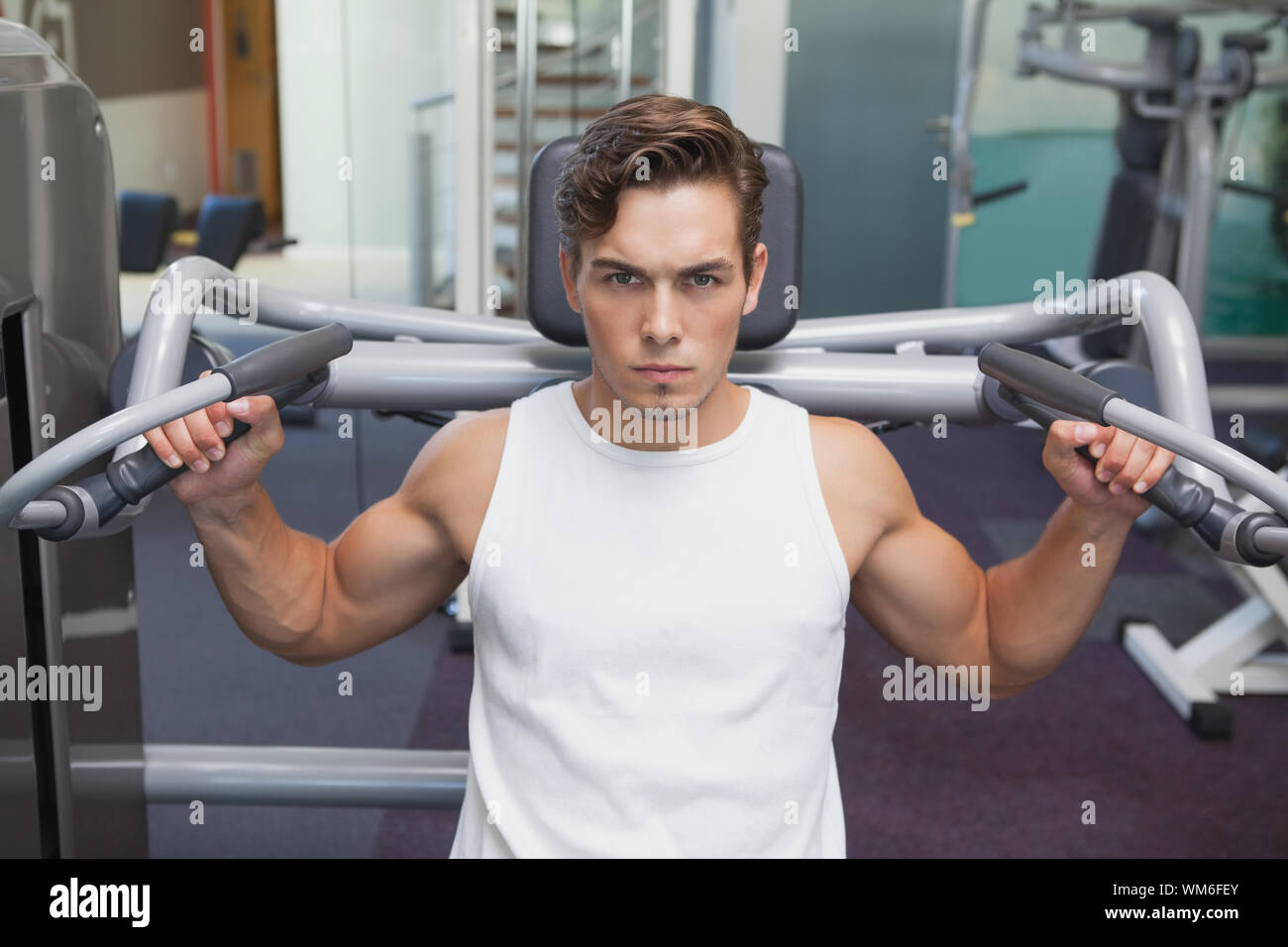 Fit man using weights machine for arms at the gym Stock Photo - Alamy