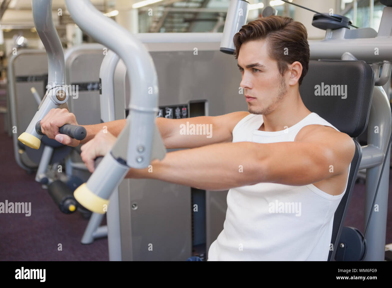 Fit man using weights machine for arms at the gym Stock Photo - Alamy