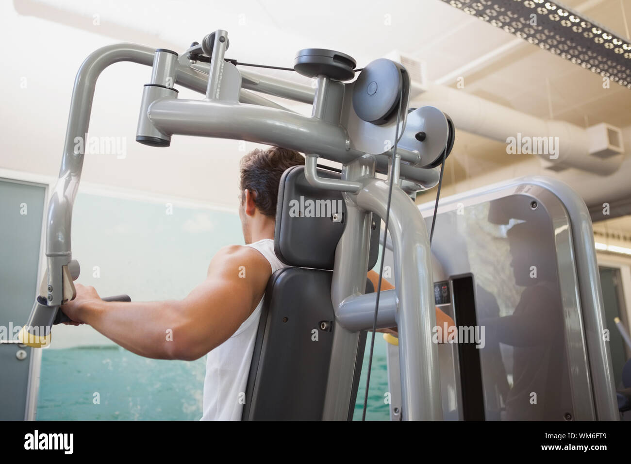 Fit man using weights machine for arms at the gym Stock Photo - Alamy