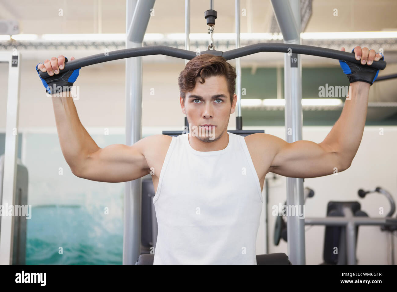Fit man using weights machine for arms at the gym Stock Photo - Alamy