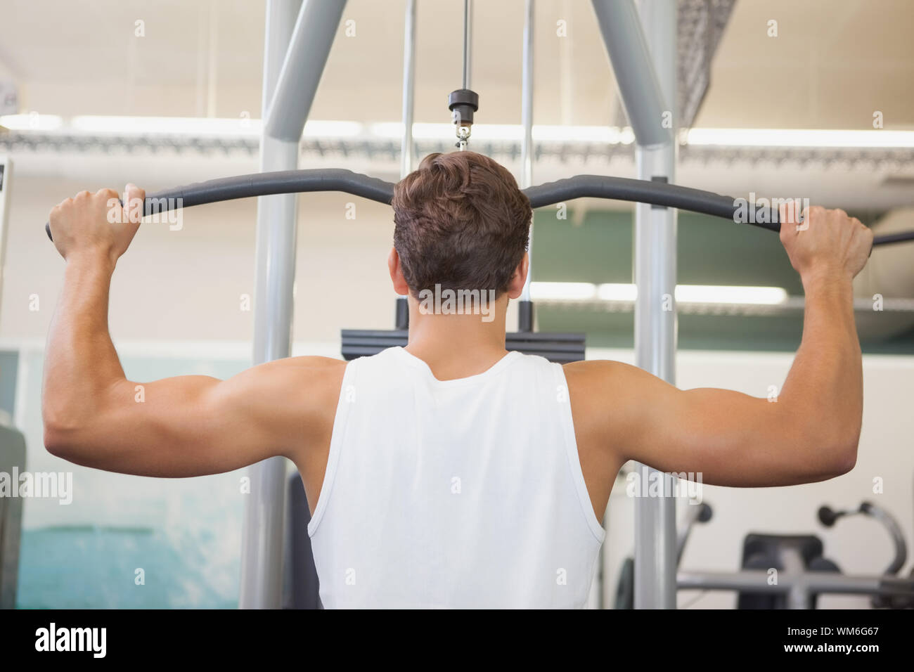 Fit man using weights machine for arms at the gym Stock Photo - Alamy