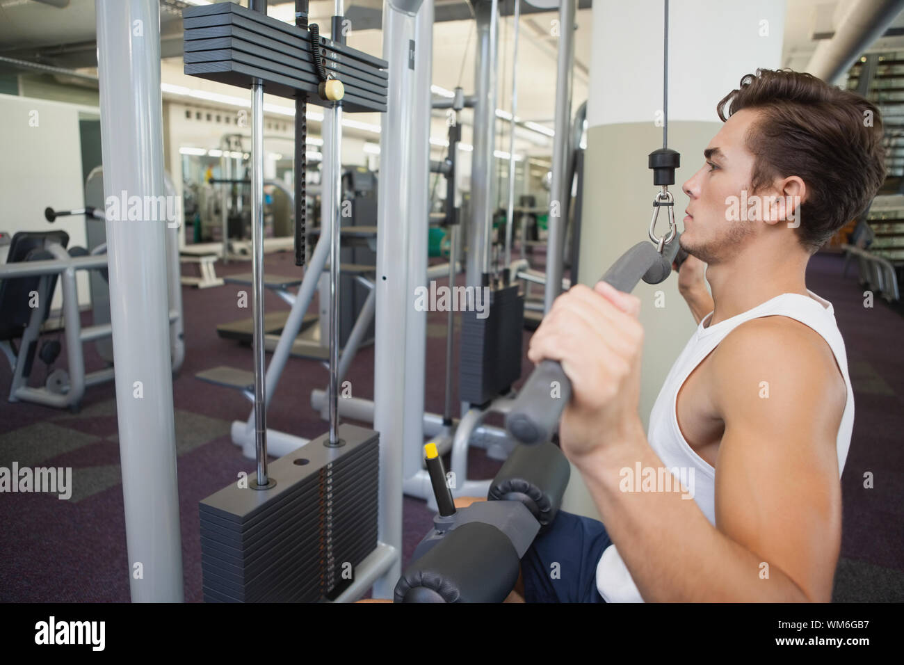 Fit man using weights machine for arms at the gym Stock Photo - Alamy