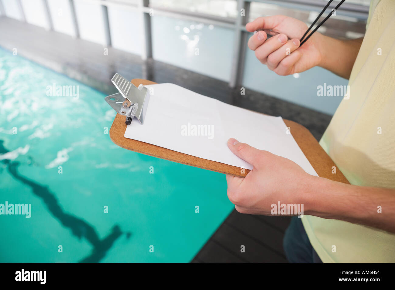 Swimming coach holding stopwatch and clipboard at the leisure center ...