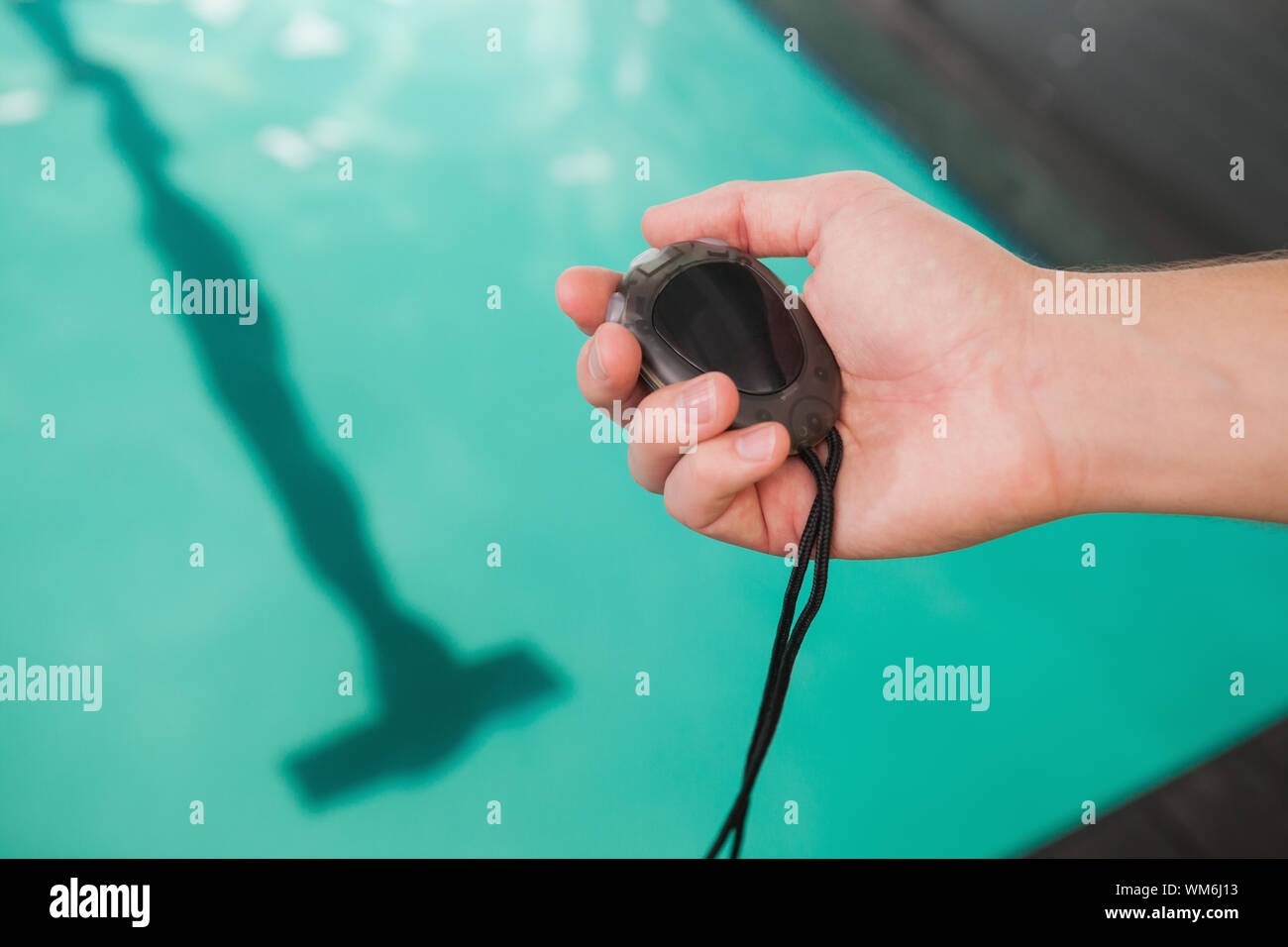 Swimming coach holding stopwatch poolside at the leisure center Stock ...