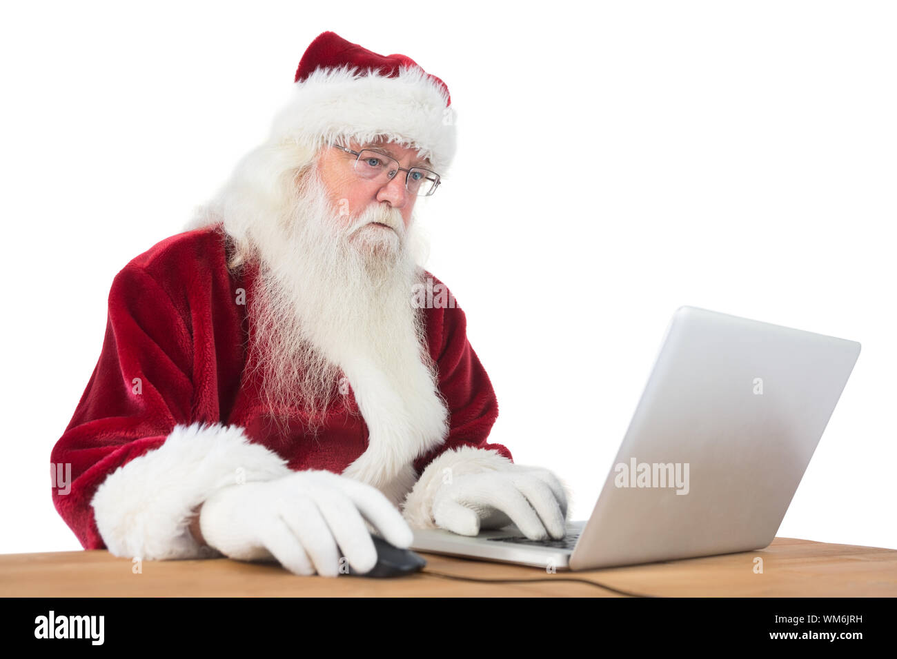 Santa surfs on the internet at a desk on white background Stock Photo ...