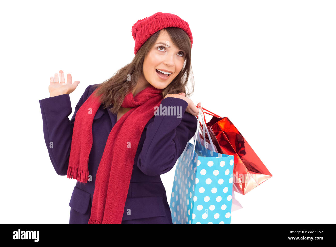 Happy brunette in winter clothes holding shopping bags on white ...
