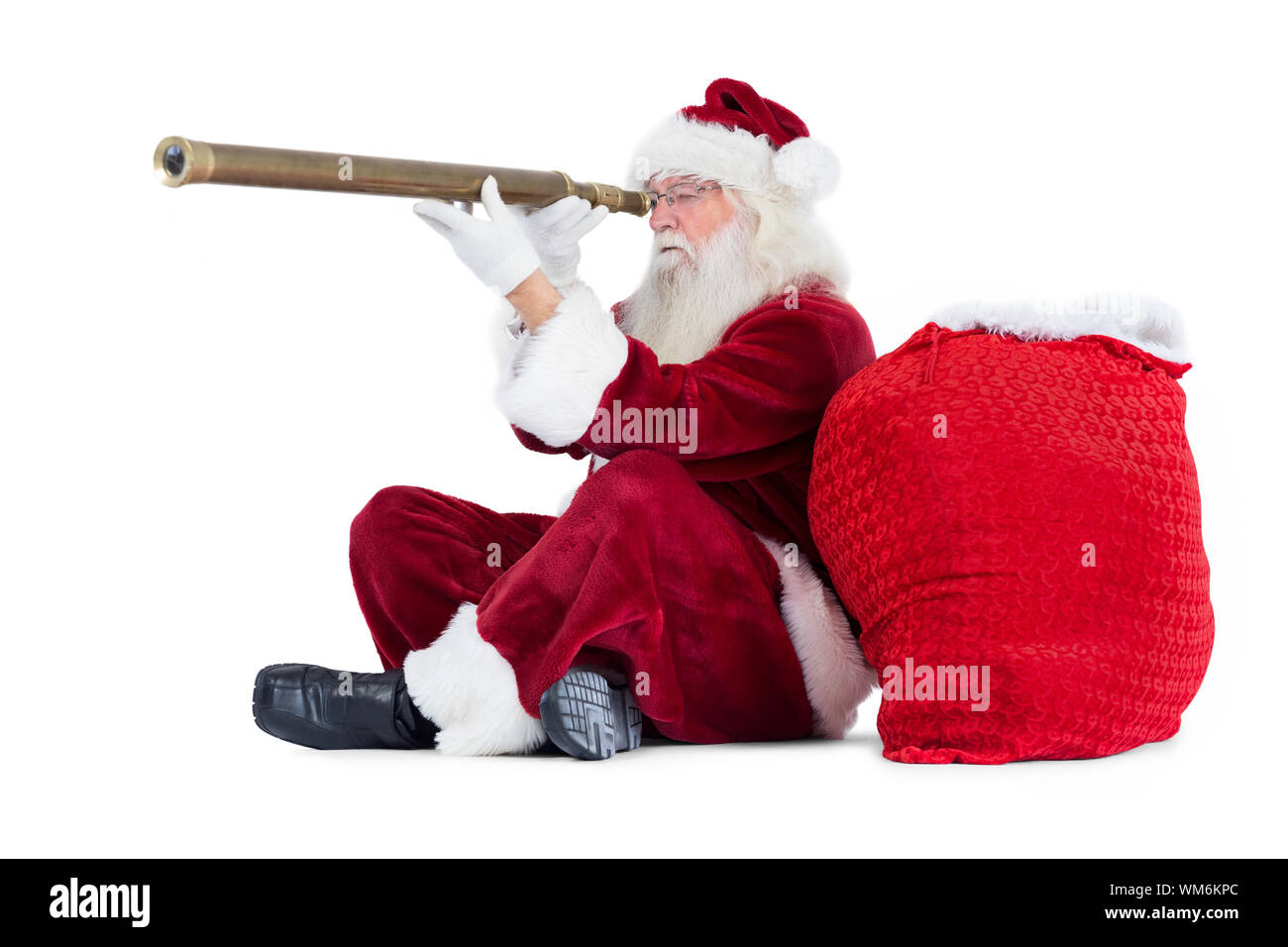 Santa is looking through his telescope while he sits next to his bag on ...