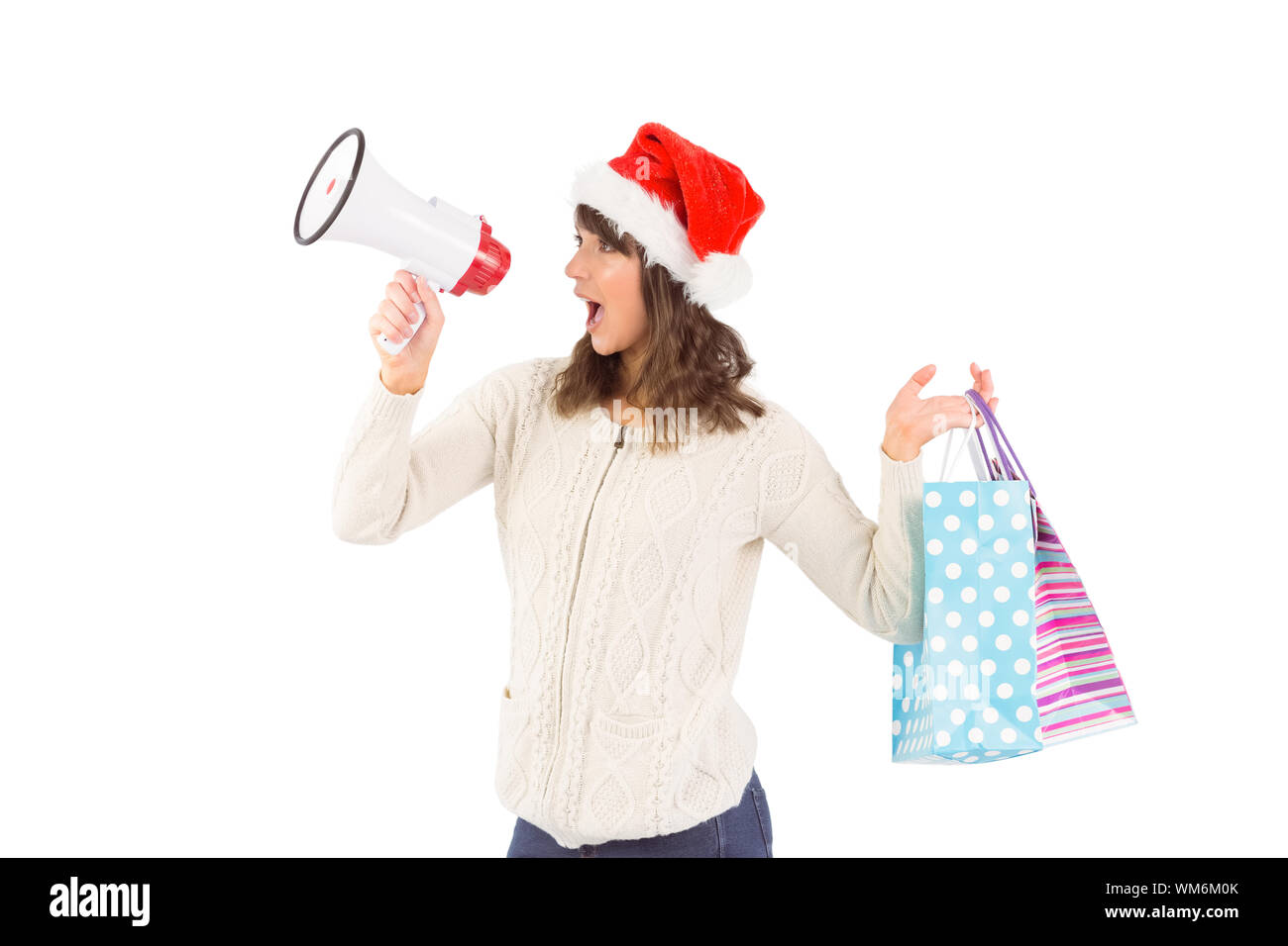 Festive brunette holding megaphone and bags on white background Stock ...