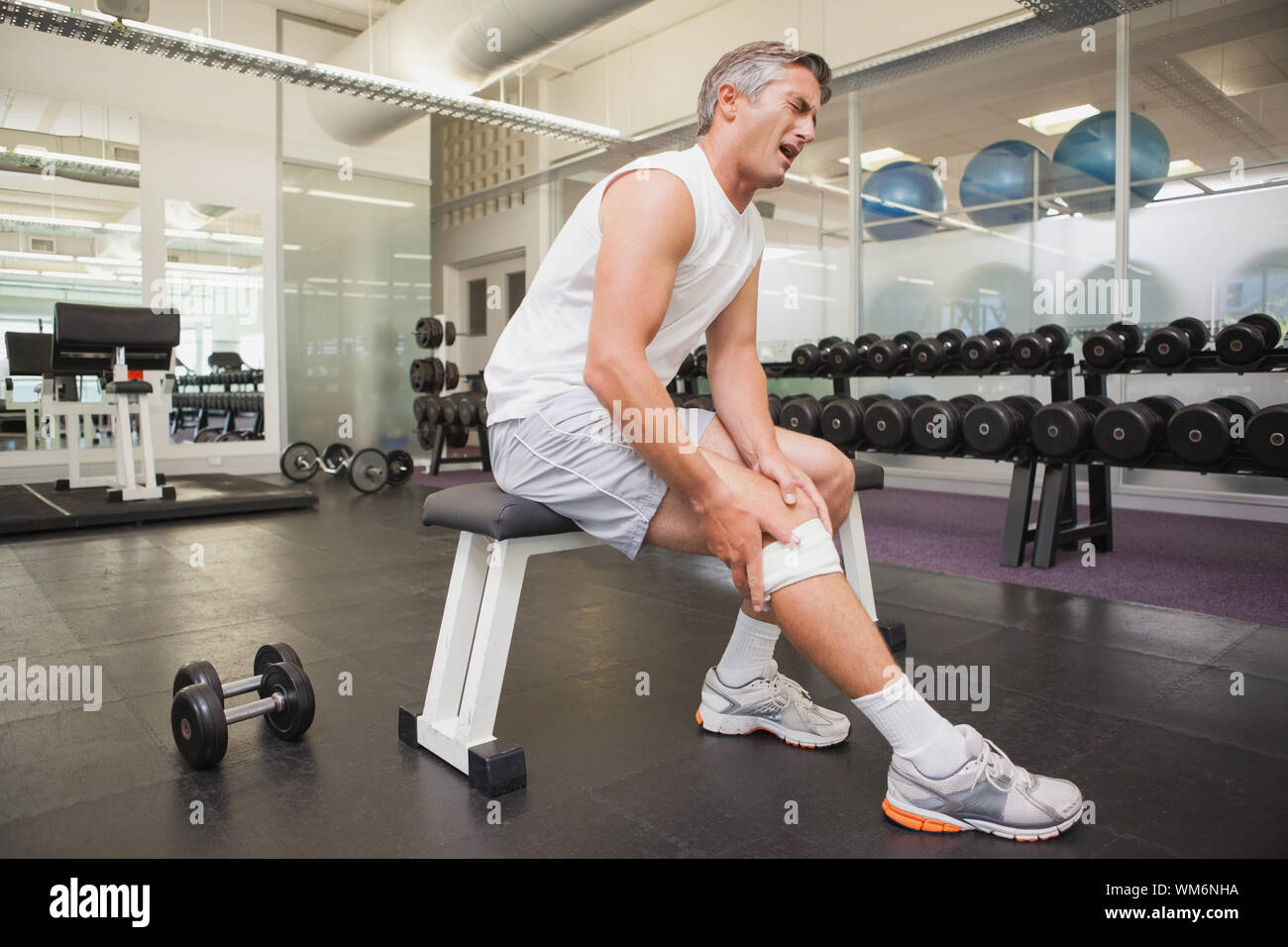 Injured man gripping his knee in the weights room at the gym Stock ...