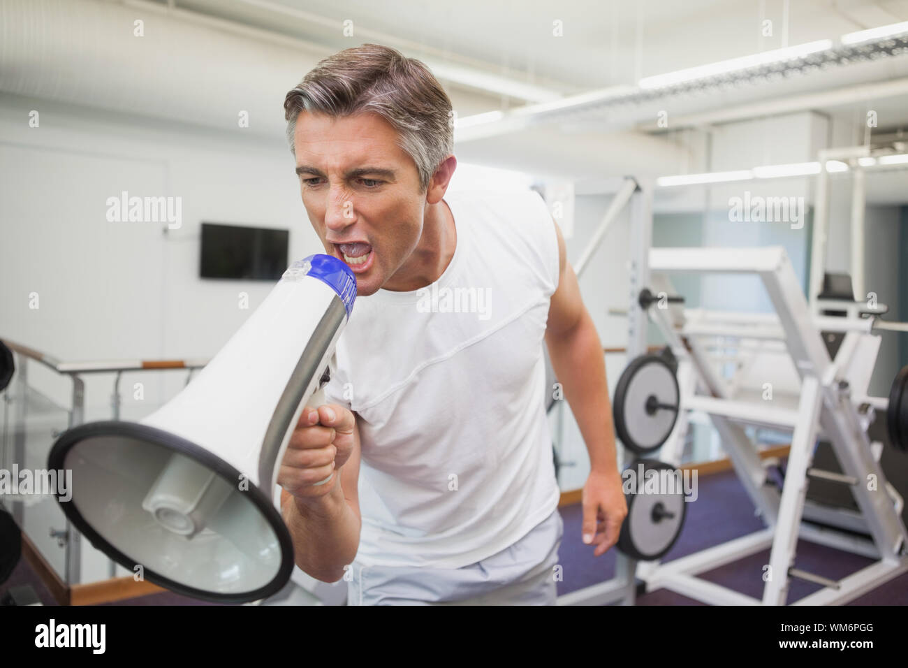 Angry personal trainer shouting through megaphone at the gym Stock ...