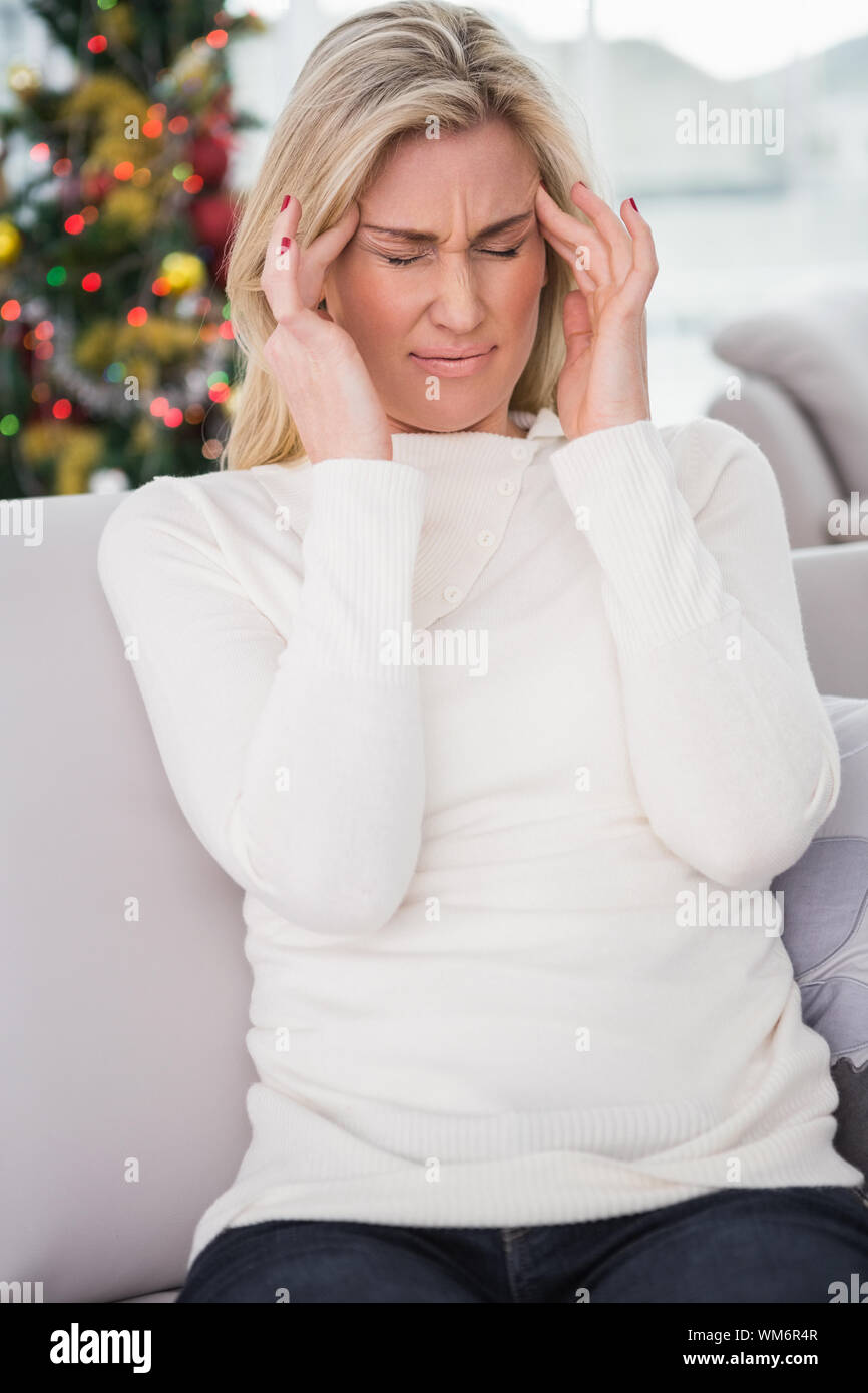 Blonde getting a headache on christmas day at home in the living room ...