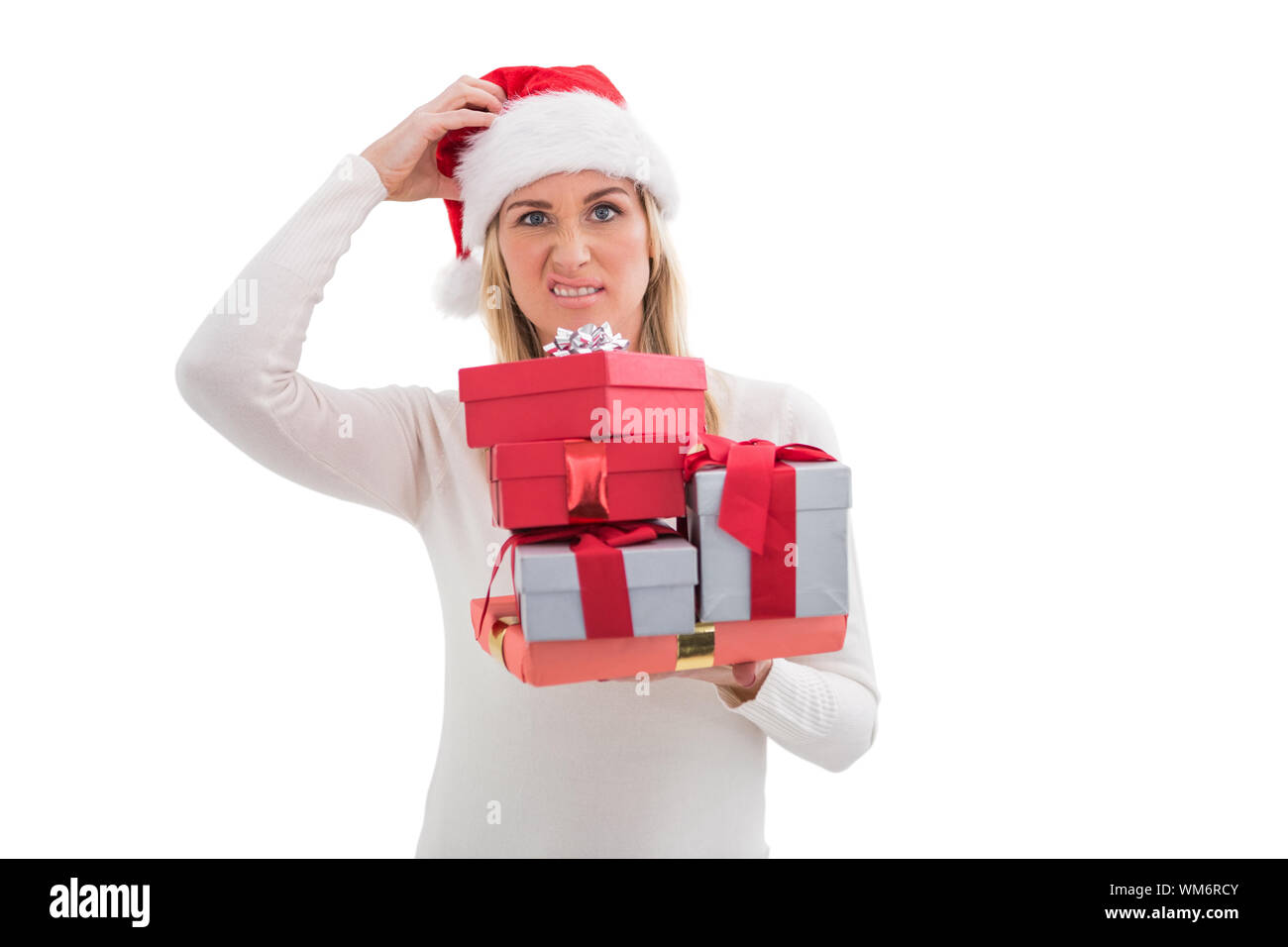 Confused blonde in santa hat holding gifts on white background Stock ...