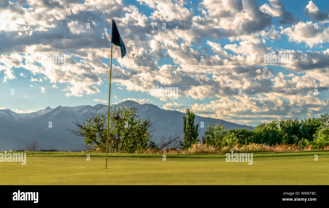 Panorama Focus on the flagstick of a golf course against trees mountain ...