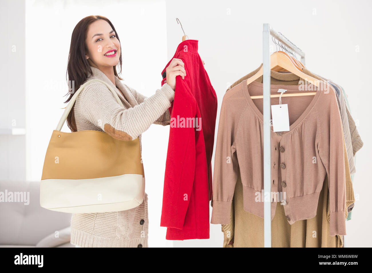 Pretty brunette picking out jacket at clothes store Stock Photo - Alamy