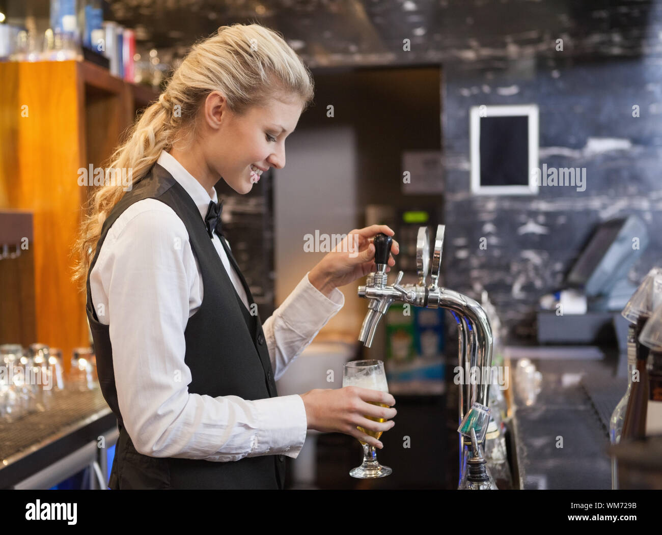 Barmaid pulling a glass of beer in a bar Stock Photo - Alamy