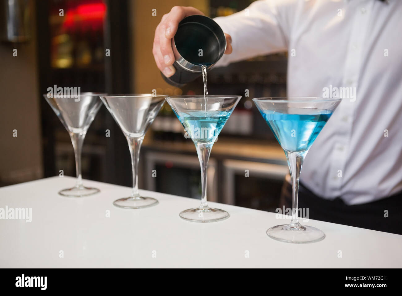 Bartender pouring cocktail into glasses in a bar Stock Photo - Alamy