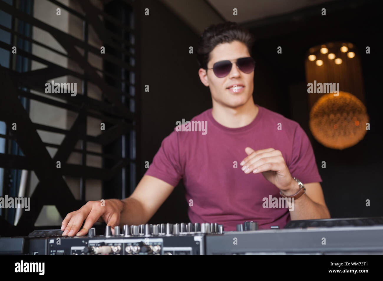 Cool dj in sunglasses working on a sound mixing desk at the nightclub ...