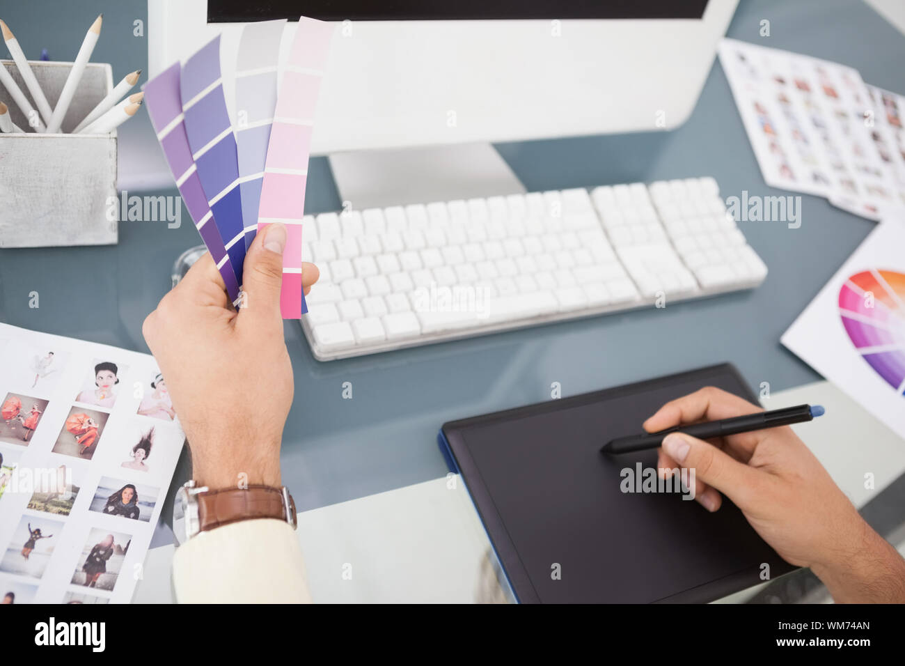 Designer working at desk using digitizer and colour sample in his ...