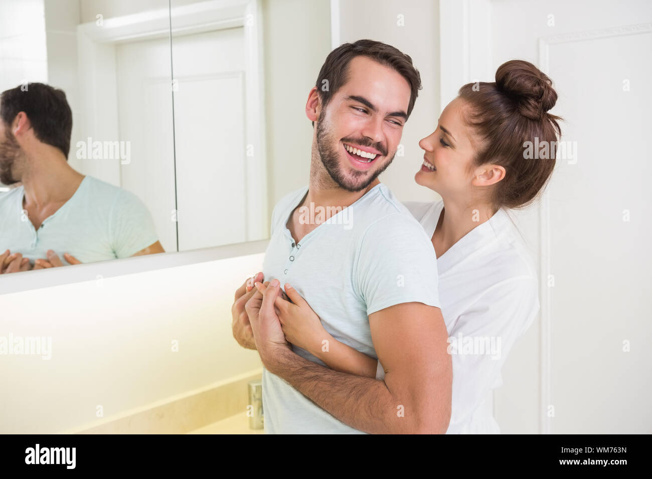 Young couple hugging and smiling at each other at home in the bathroom ...