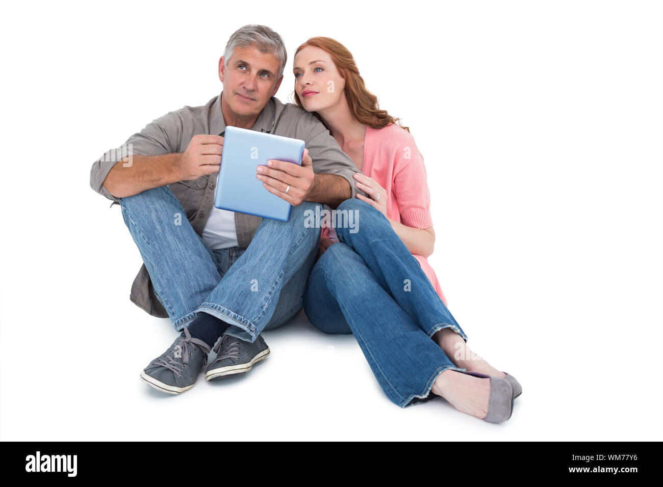 Casual couple sitting using tablet on white background Stock Photo - Alamy