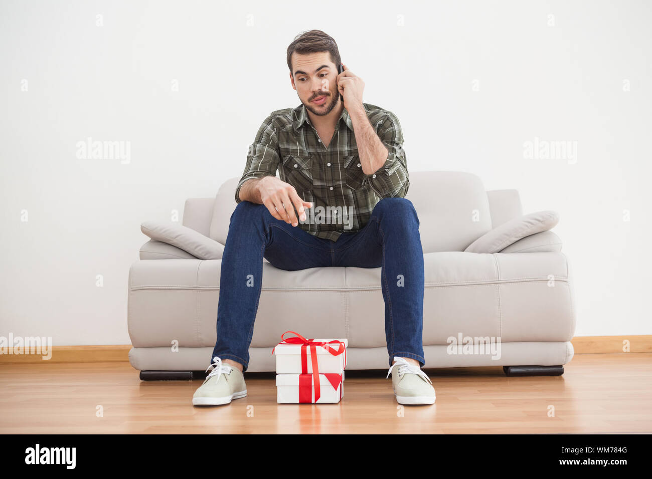 Confused man looking at gifts on floor at home in the living room Stock ...