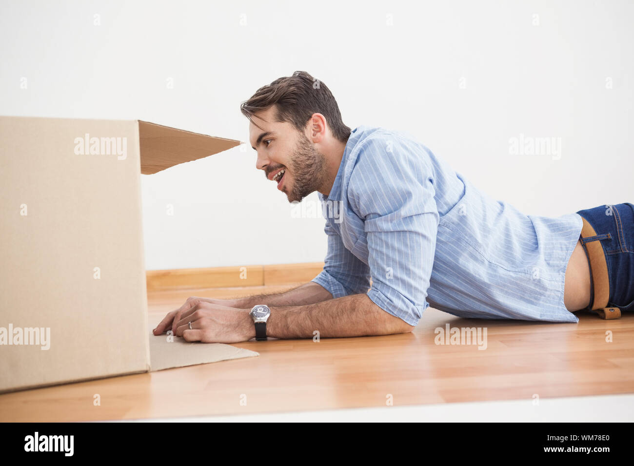 Smiling man looking inside cardboard box at home in the living room ...