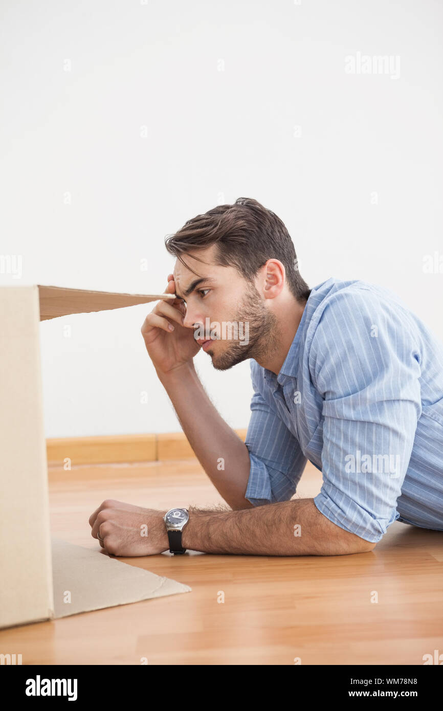Casual man looking inside cardboard box at home in the living room ...