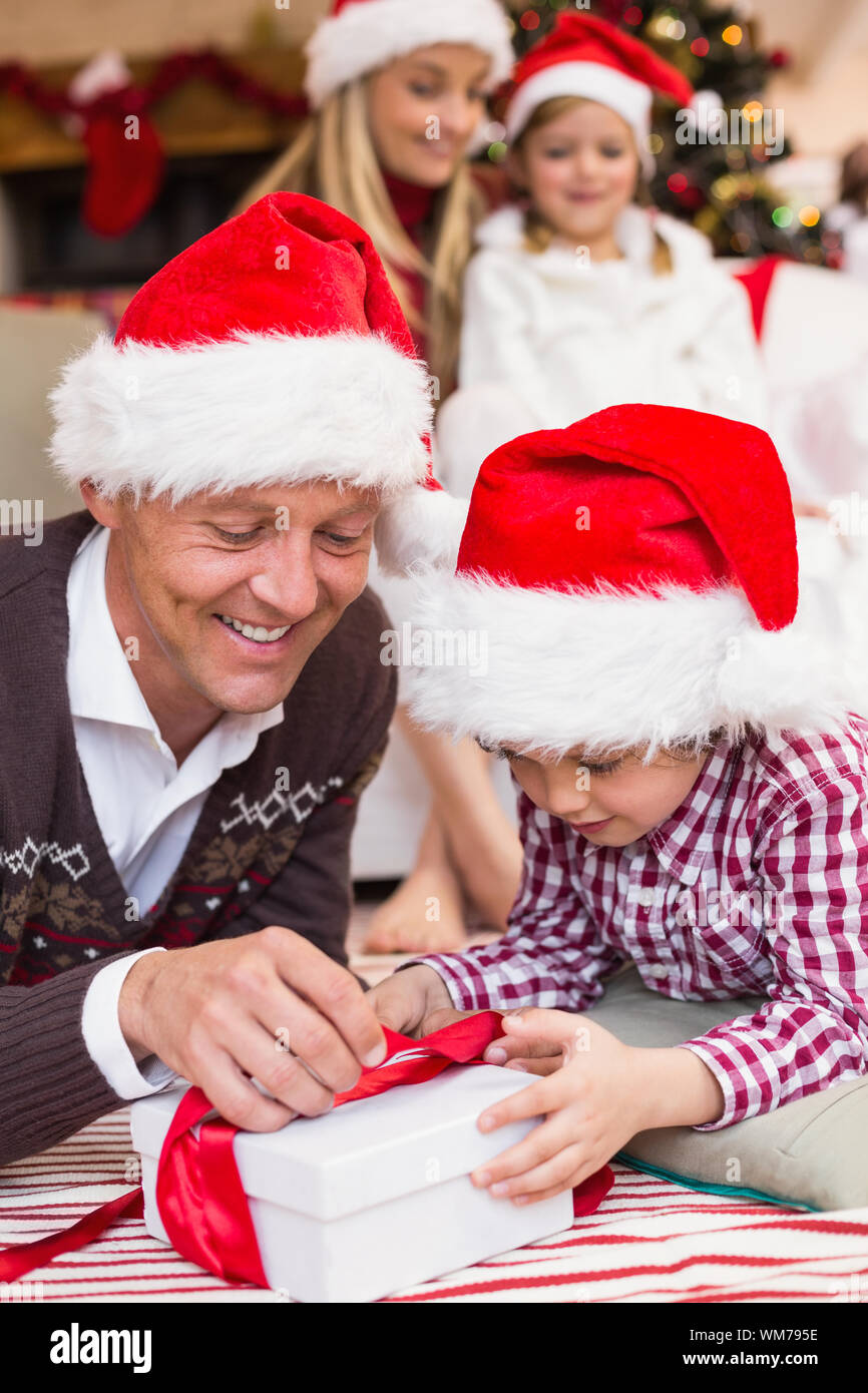 Festive father and son opening christmas present at home in the living ...