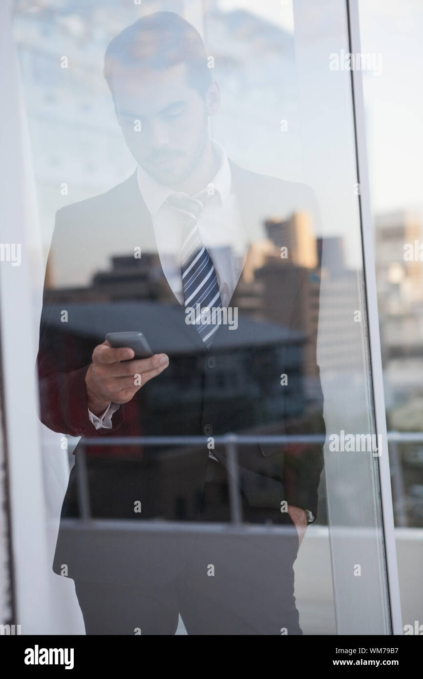 Businessman sending a text seen through window in his office Stock ...